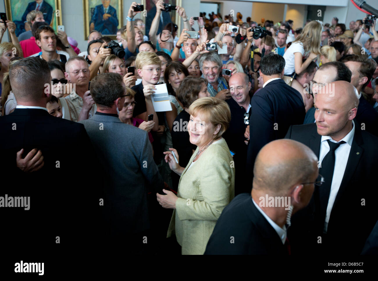 German Chancellor Angela Merkel (CDU, C) signs autographs and talks to ...