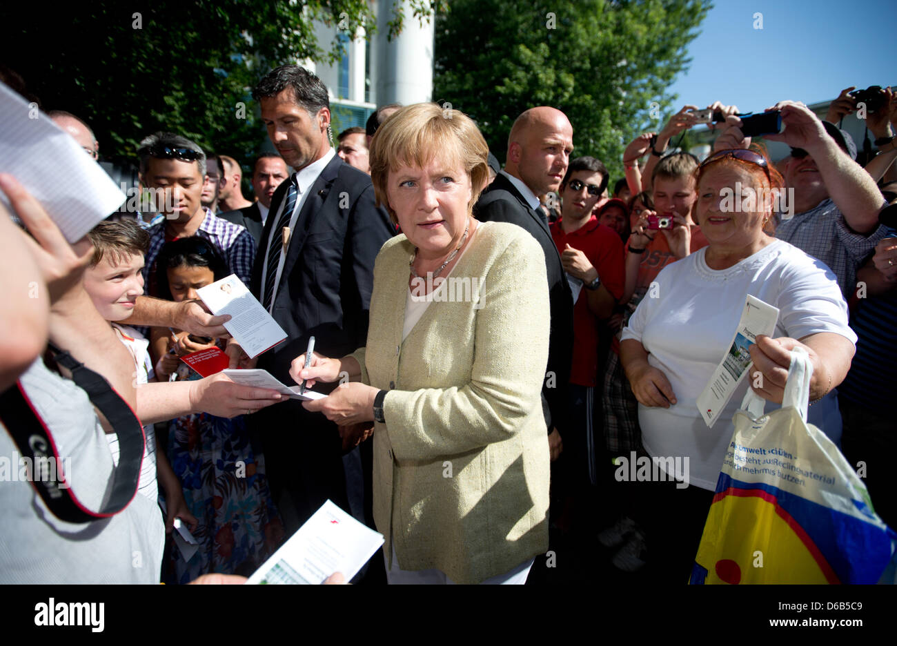 German Chancellor Angela Merkel (CDU, C) signs autographs and talks to ...