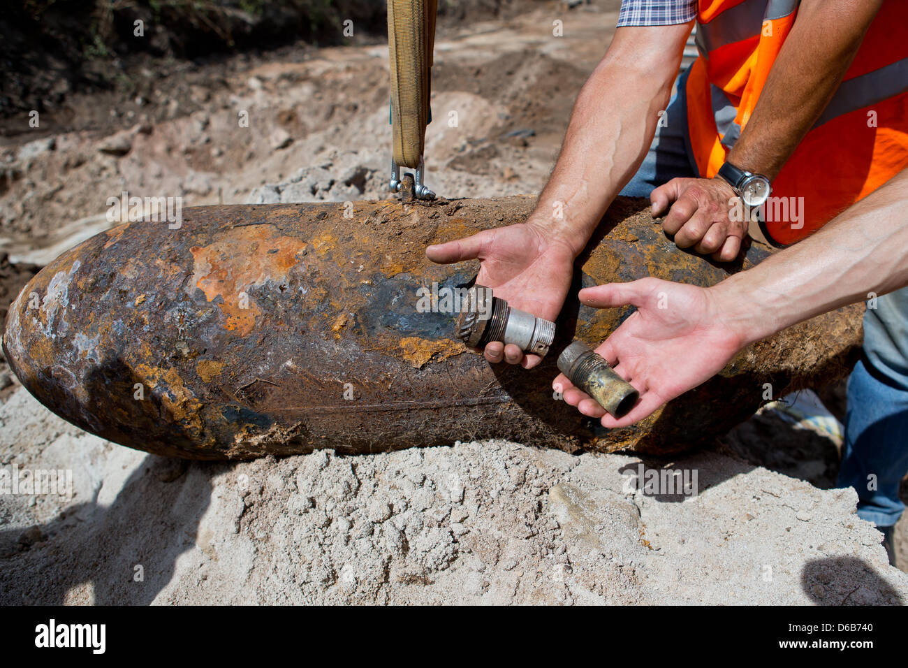 Two demolition experts hold fuzes next to a defused aerial bomb from ...