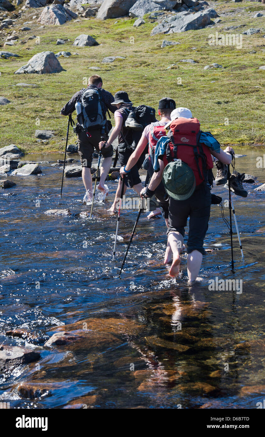 A group of hikers cross a stream on their way to a local mountain in ...