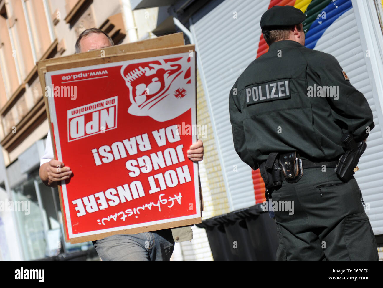 A man carries posters of the right-wing extremist party NPD from a ...