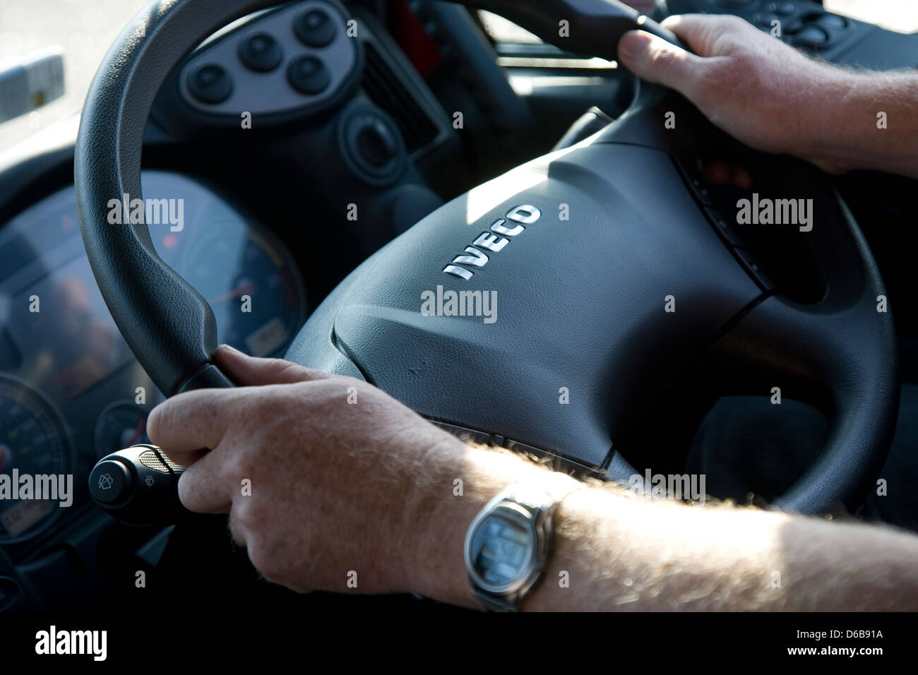 Interior cab view showing hands holding steering wheel of Iveco lorry ...