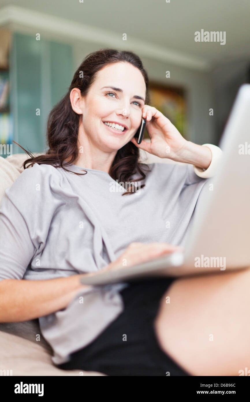 Woman on cell phone using laptop Stock Photo - Alamy