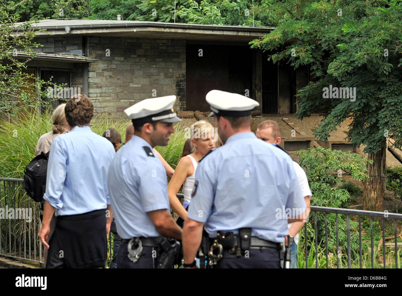 Police officers and visitors stand in front of a compound at the zoo in ...