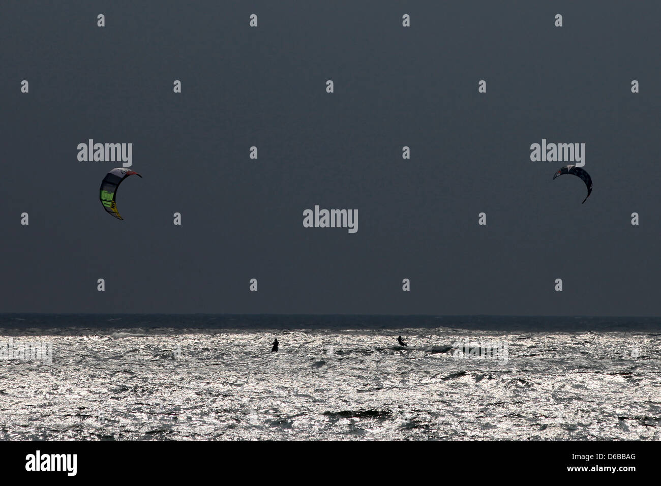 Two kite surfers enjoy their sport underneath a dark sky at the North ...