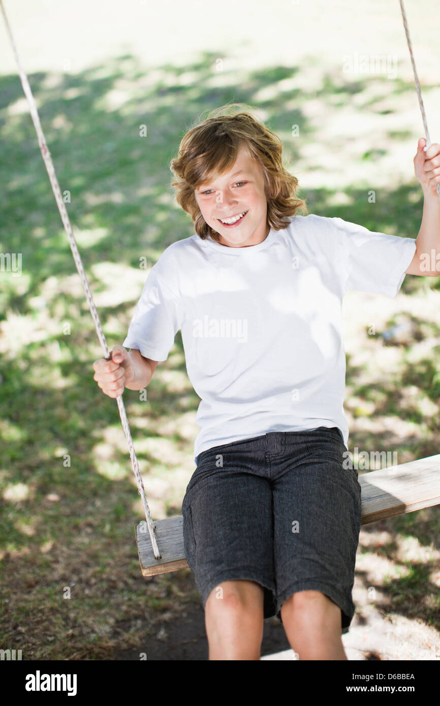 Boy playing on swing in park Stock Photo - Alamy