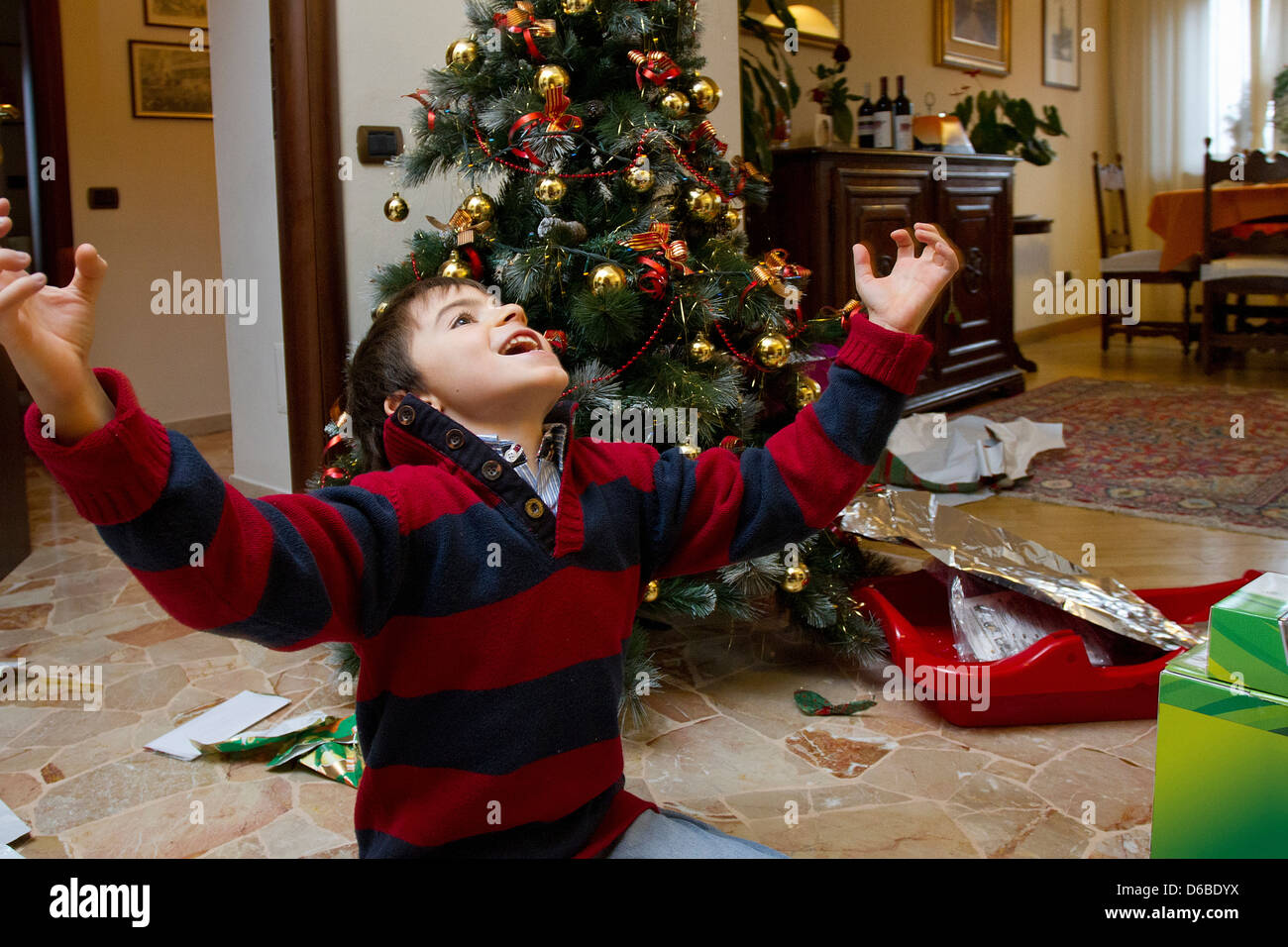 Boy cheering by Christmas tree Stock Photo - Alamy