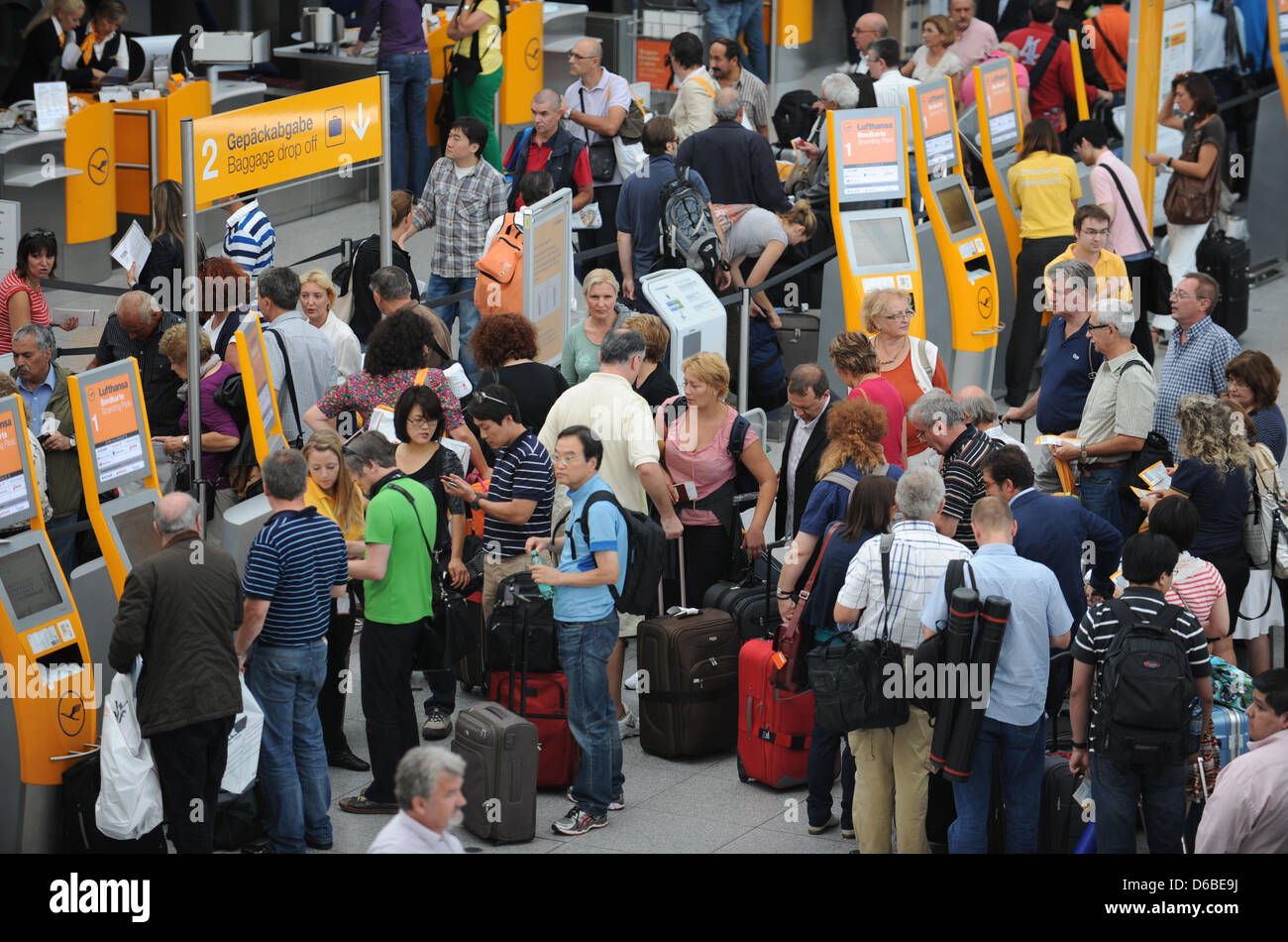 Travellers queue in front of the check-in counters of airline Lufthansa ...