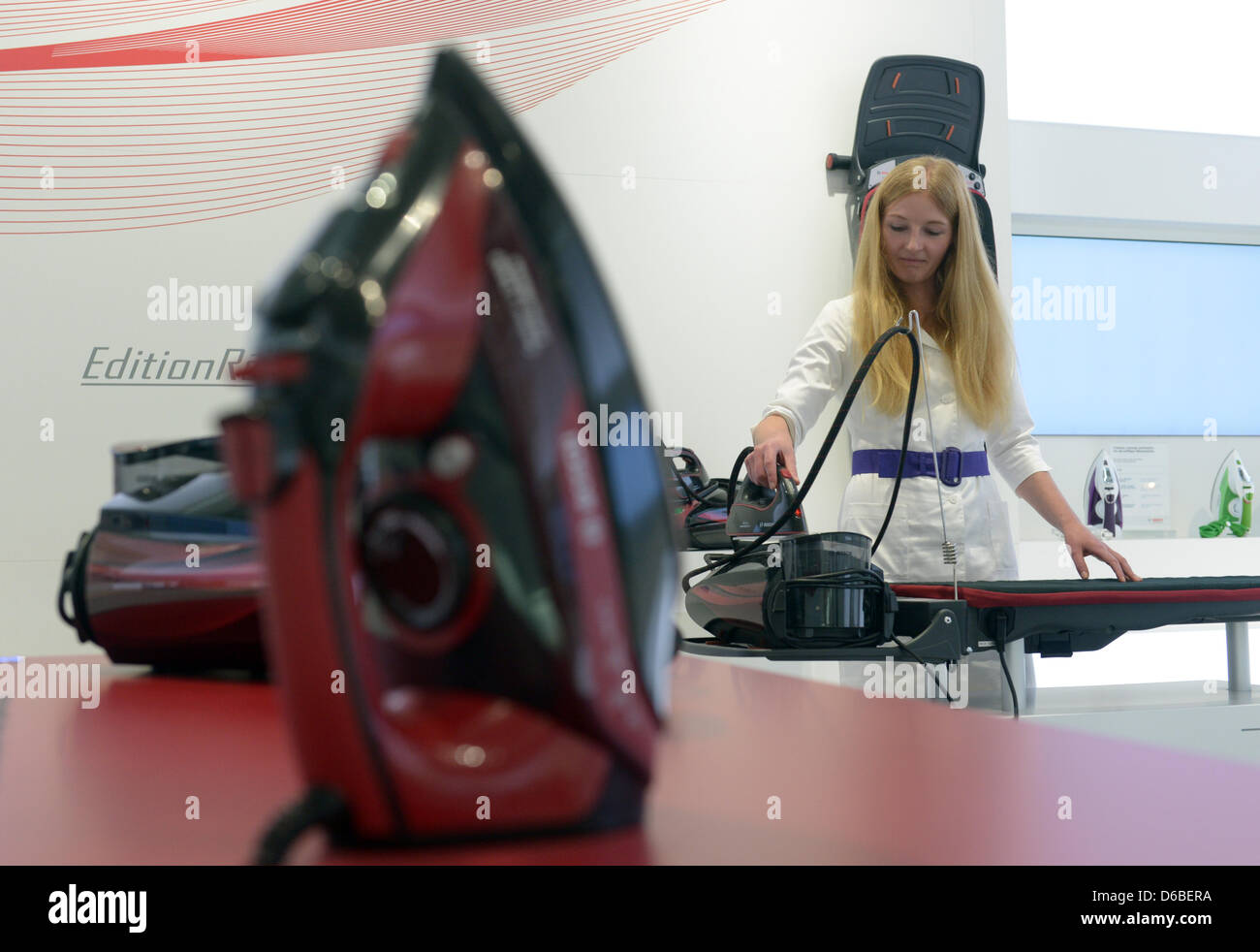 A hostess tries out an iron at the booth of German electrical appliance ...