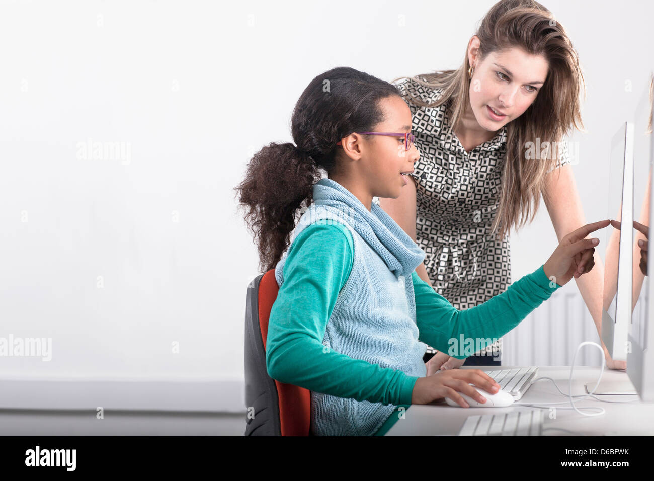 Teacher helping student use computer Stock Photo - Alamy