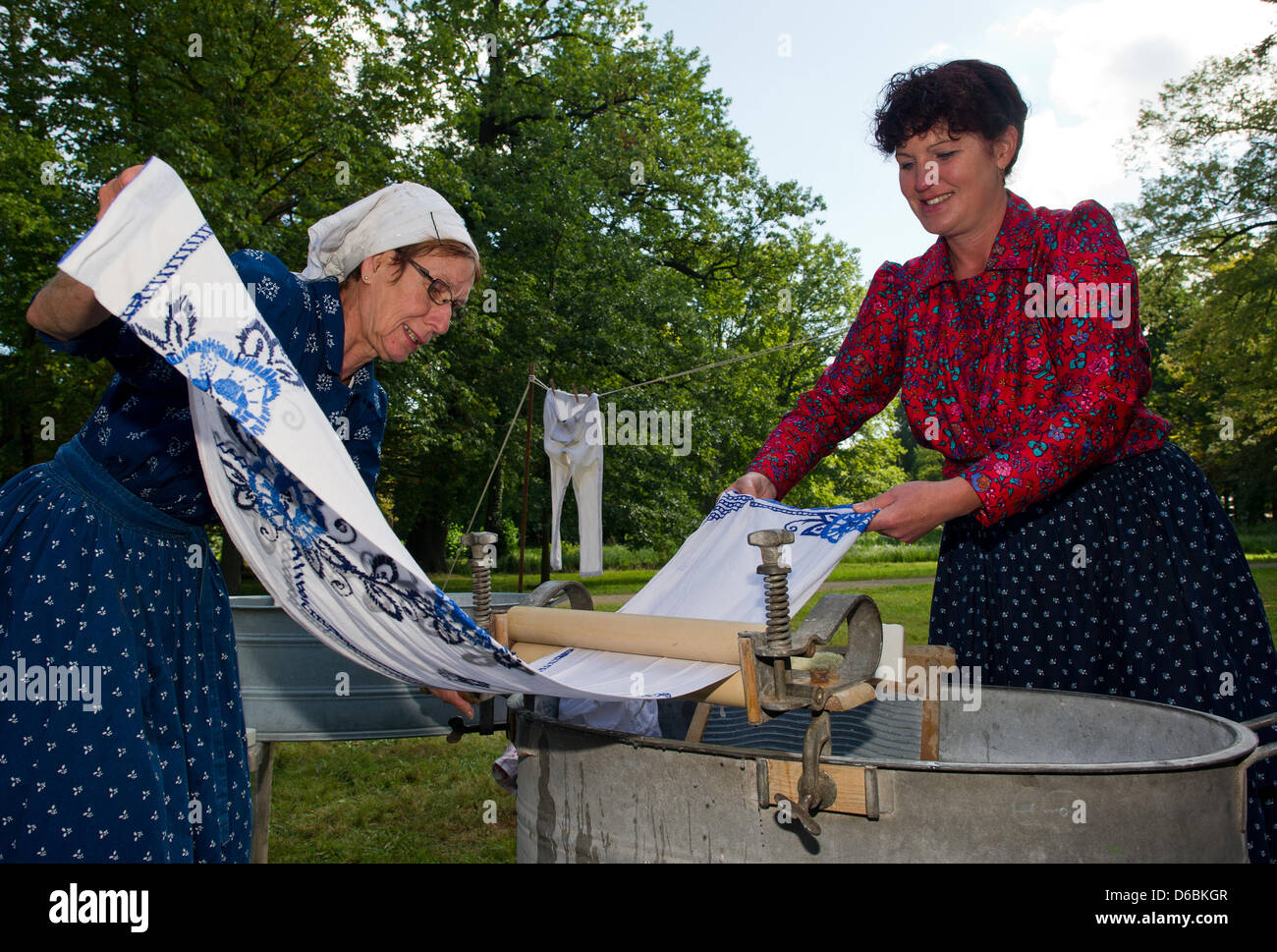 Two women wear traditional work dress and show how the laundry used to ...