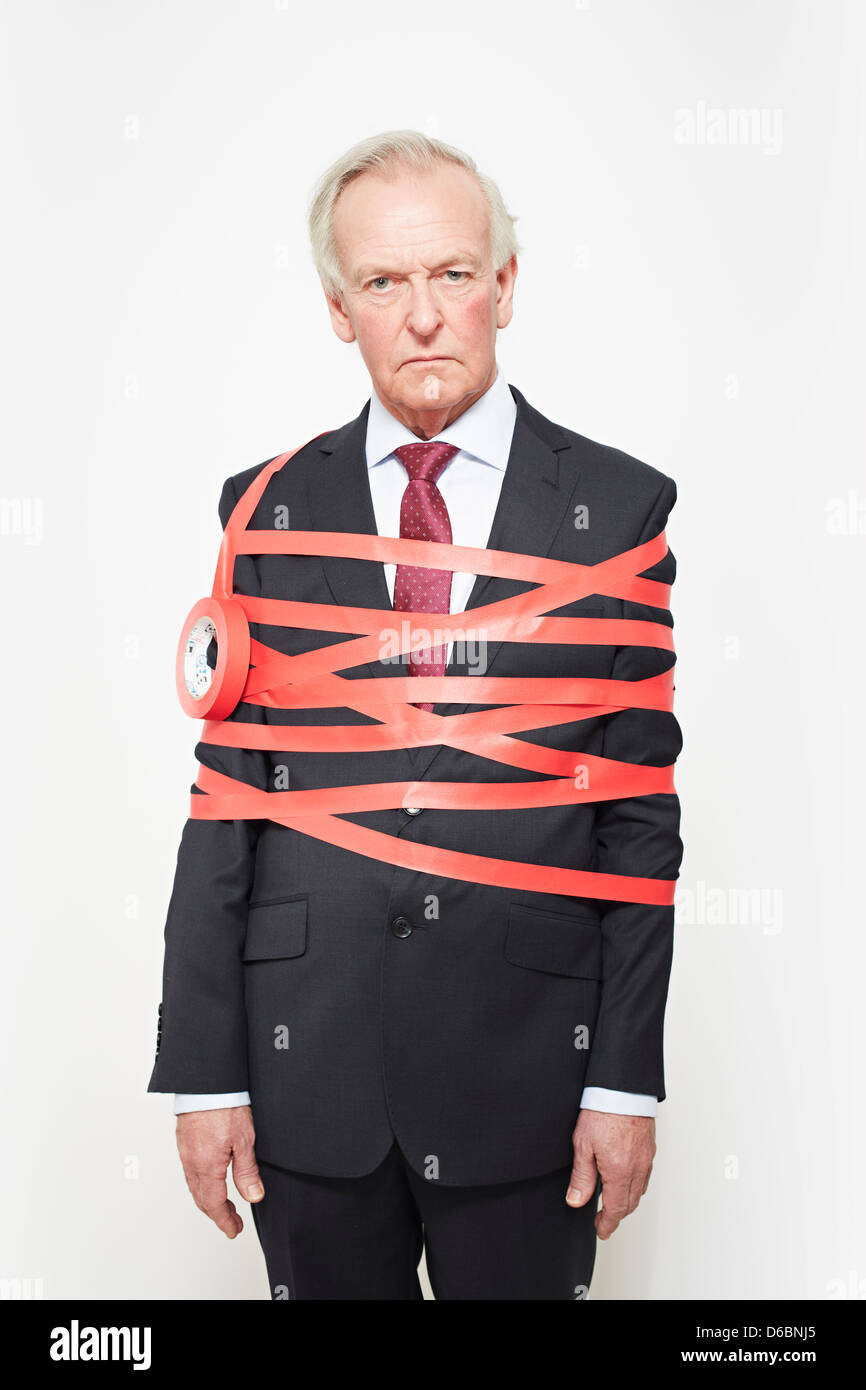 Businessman wrapped in red tape Stock Photo - Alamy