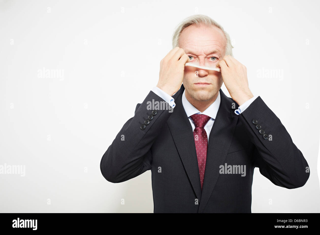 Businessman pulling on mask Stock Photo - Alamy