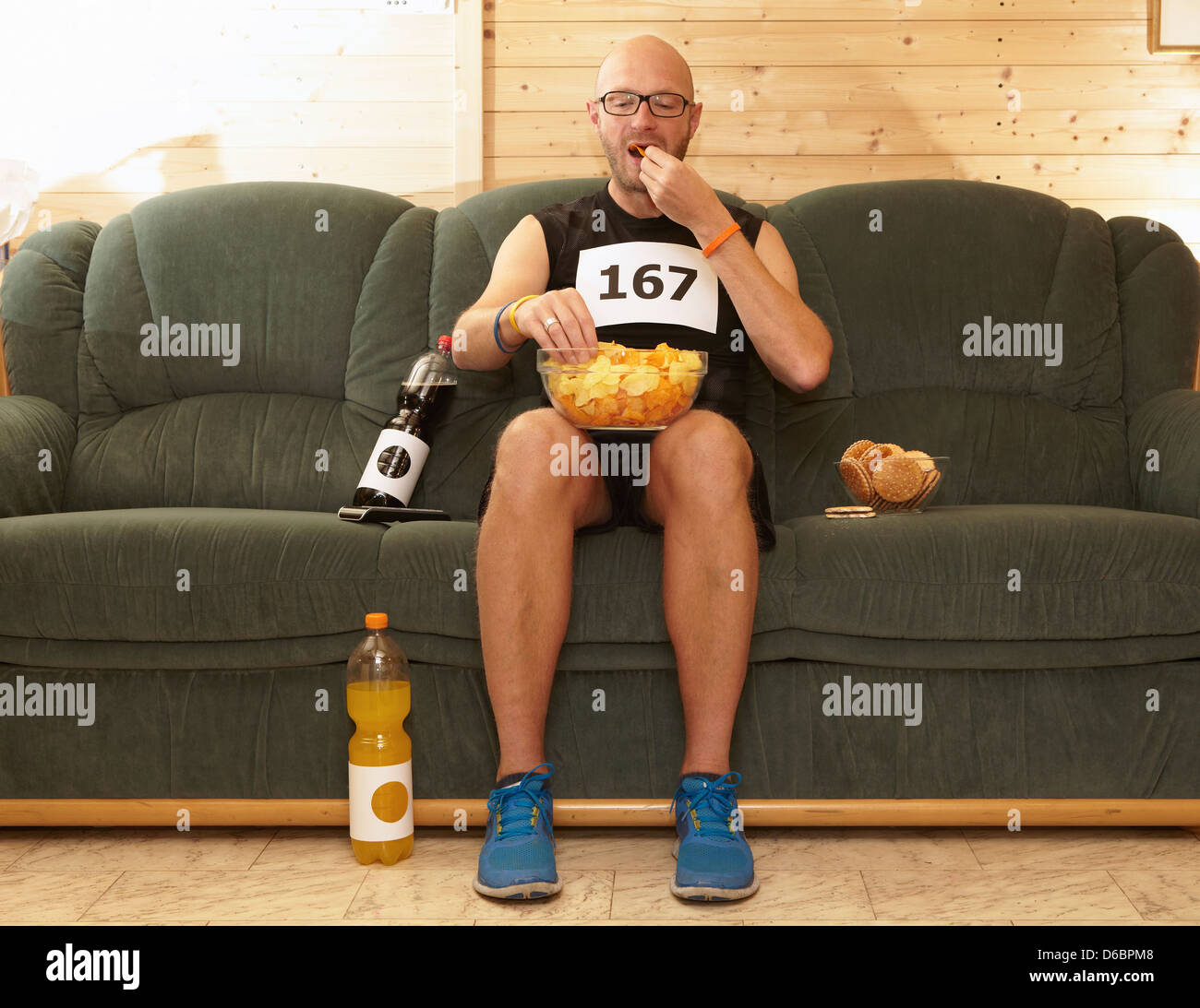 Runner eating chips on sofa Stock Photo - Alamy