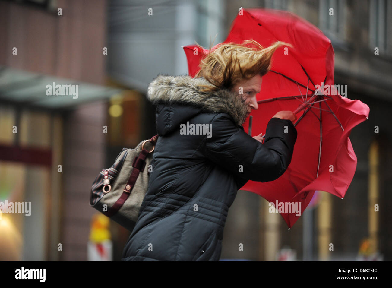 A woman fights against hurricane-force winds with her umbrella in the ...