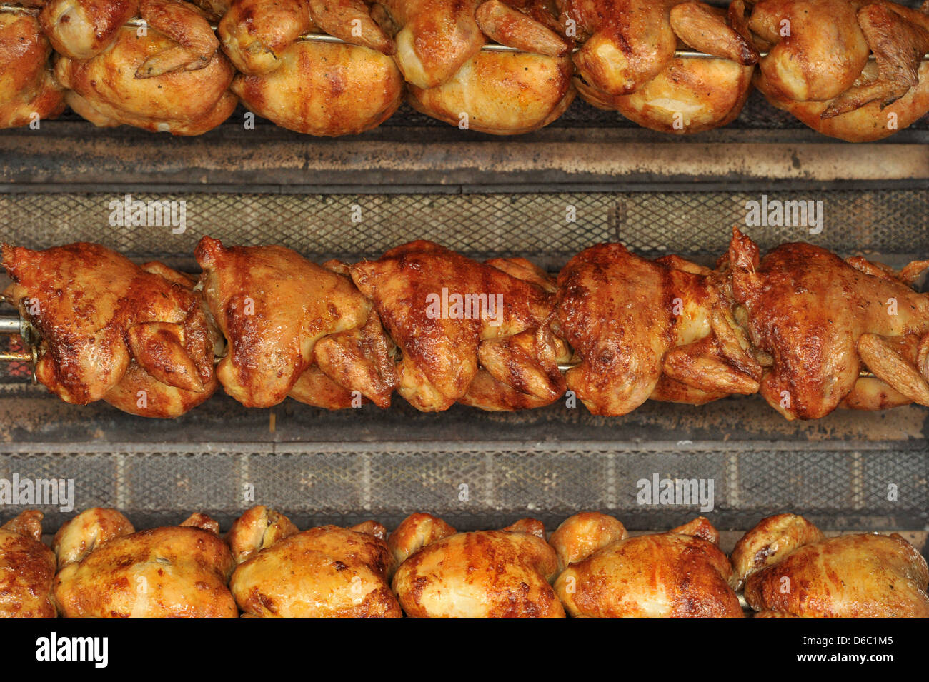 Crispy chickens rotate on a spit at a barbecue stand in Bamberg ...