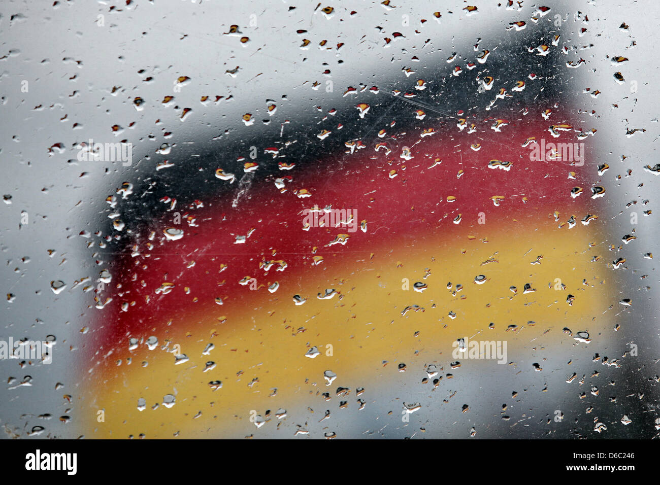 Rain drops are seen on a glass window in front of a German flag at the ...