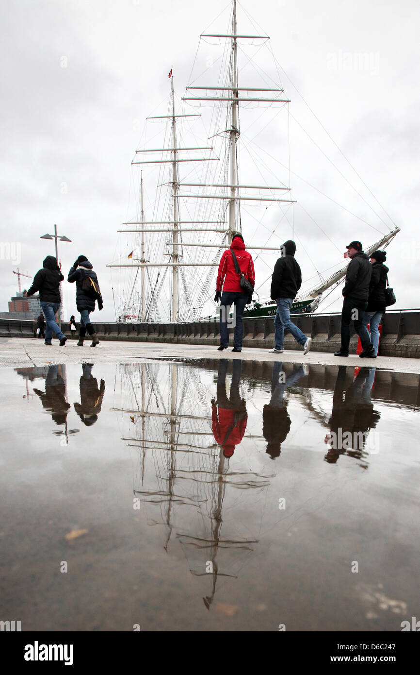 People walk past a huge puddle during wet-cold weather at the landing ...