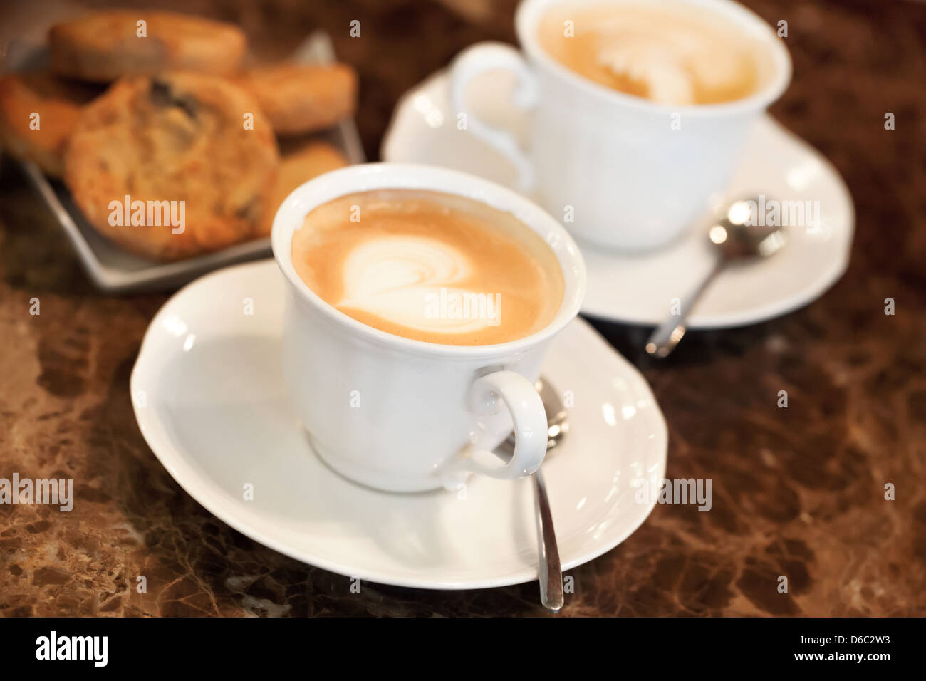 Two white cups of Cappuccino coffee with heart shaped milk foam ...