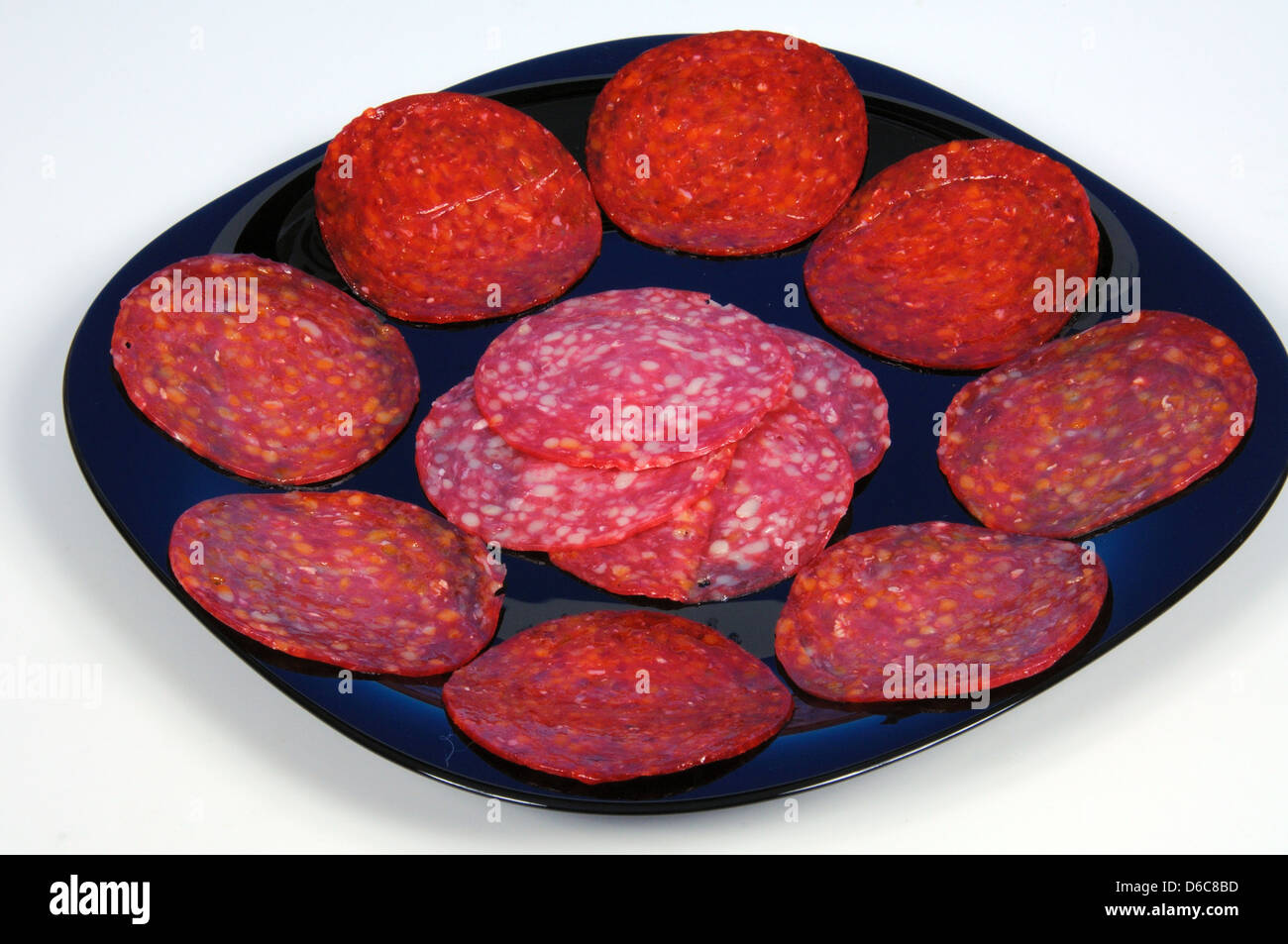 Slices of salami on a black plate against a white background Stock ...