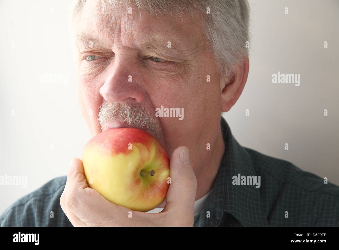 older man bites into a fresh apple Stock Photo - Alamy