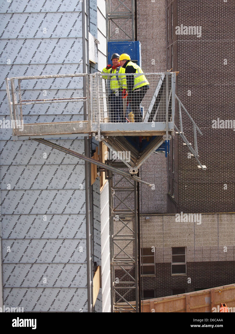 April 2013 - Construction workers on a mast climber access tower system ...
