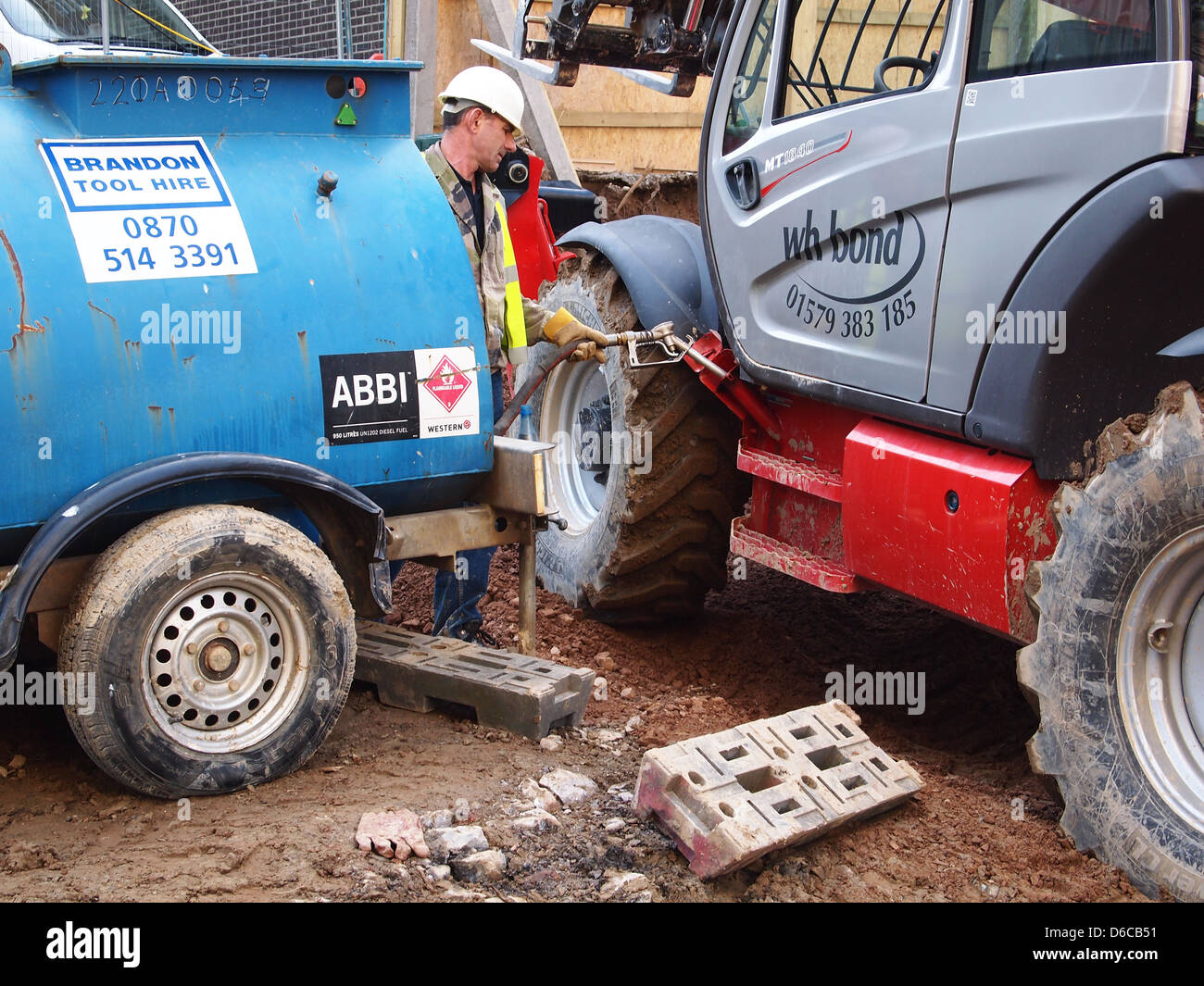 Construction site worker filling his big machine with diesel fuel on ...