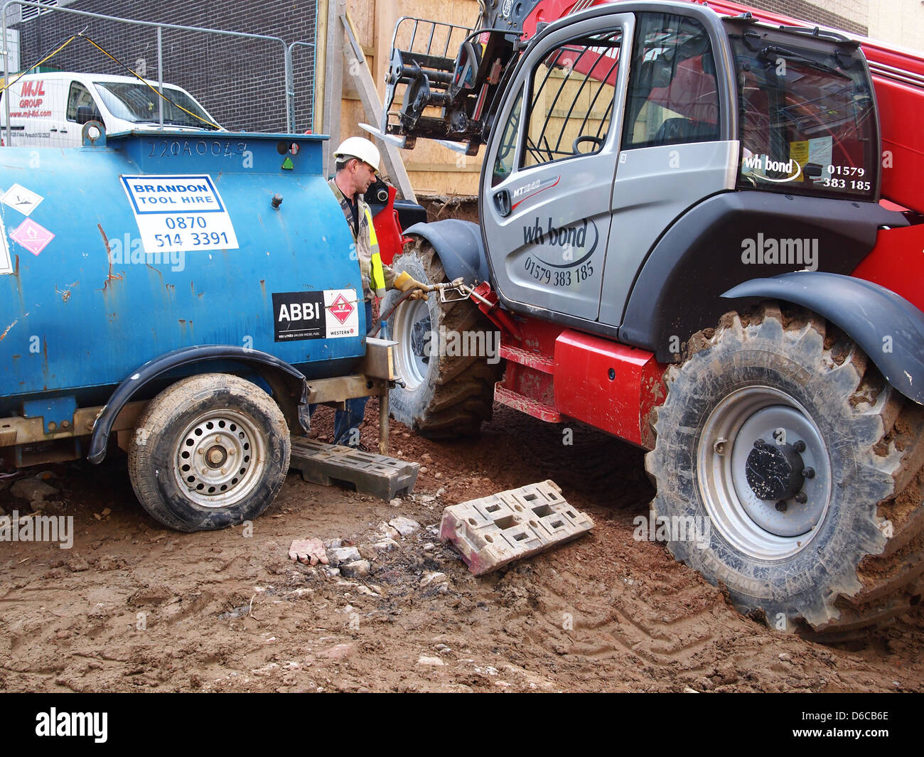 Construction site worker filling his big machine with diesel fuel on ...