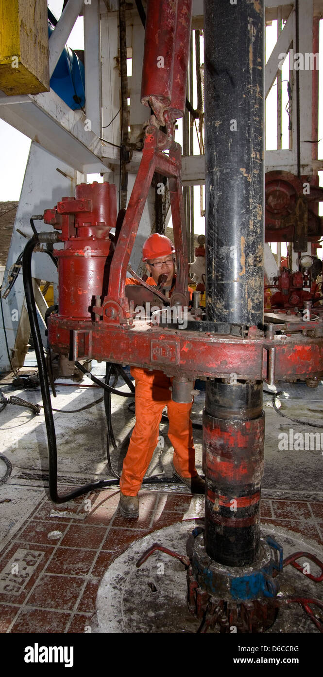 Onshore oil and gas exploration rig site with crewman connecting casing ...