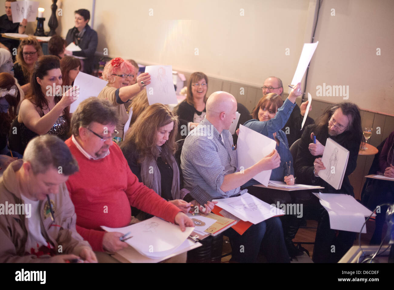 A seated audience enjoying a performance and sketching at a Dr Sketchy ...