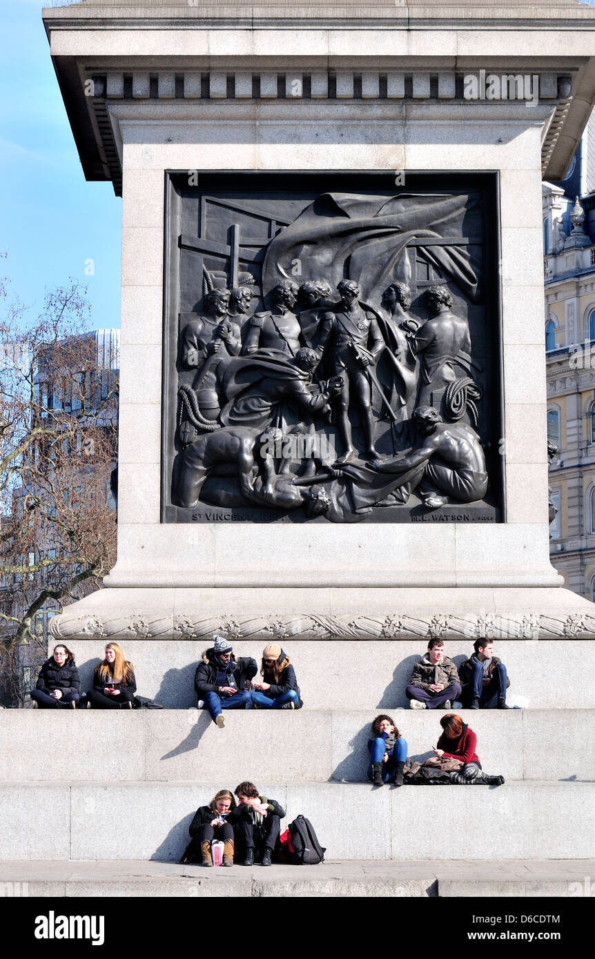 London, England, UK. People sitting on the base of Nelson's Column ...
