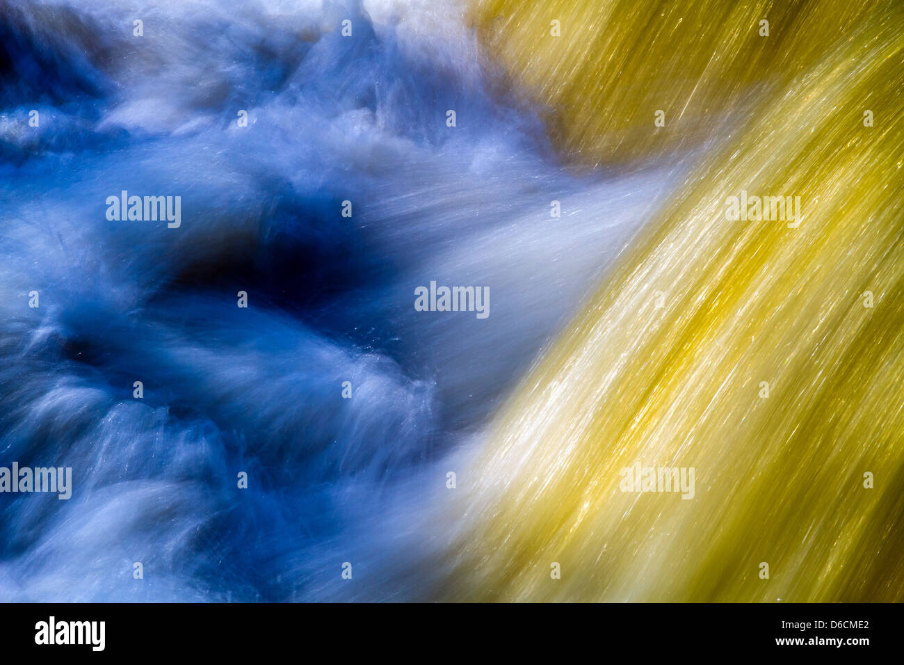 Blue and yellow rushing water on a waterfall Stock Photo - Alamy