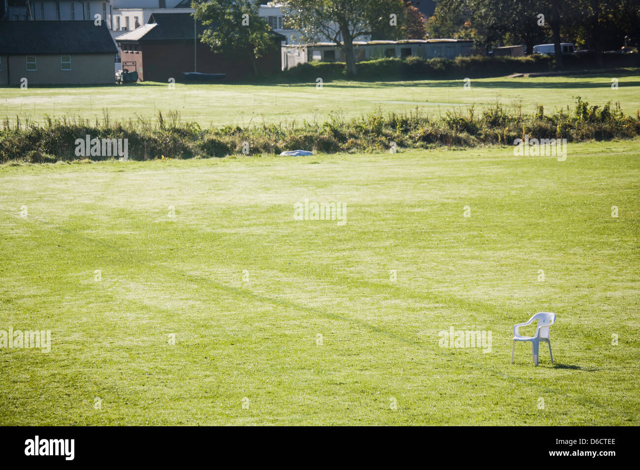 Empty playing field with one white plastic chair to the right ...