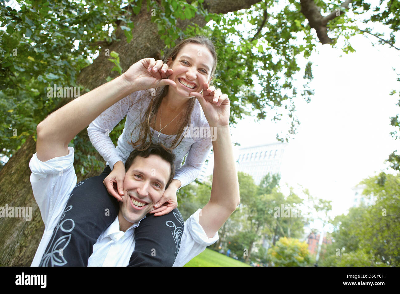 Girl sitting on guy's shoulders in park Stock Photo - Alamy