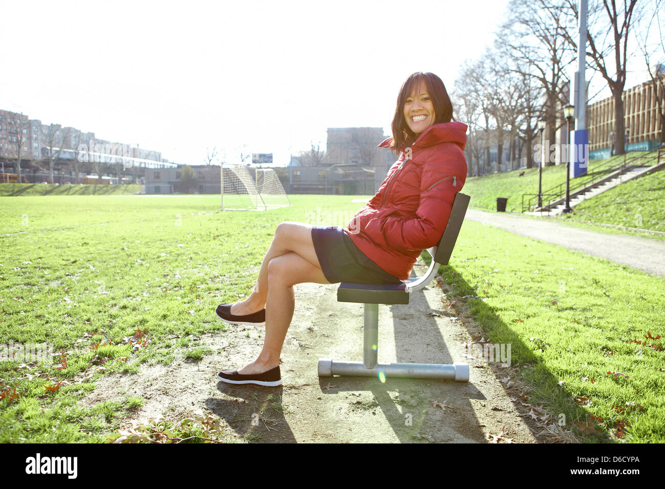 Woman sitting on bench on side of soccer field Stock Photo - Alamy