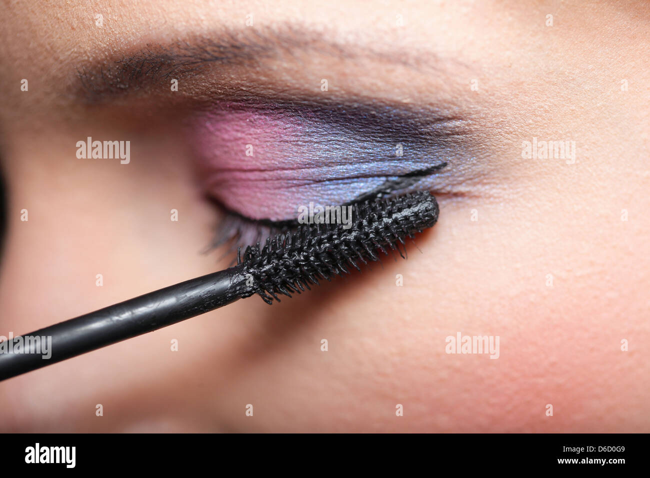 Closeup young woman applying mascara makeup on eyes by brush Stock ...