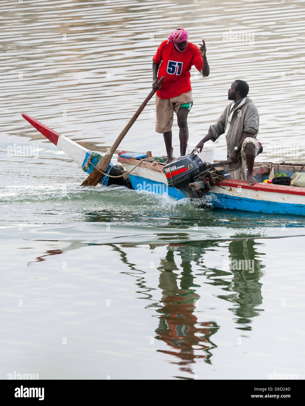 Two Senegalese man in a small boat arguing, one steering with an oar ...