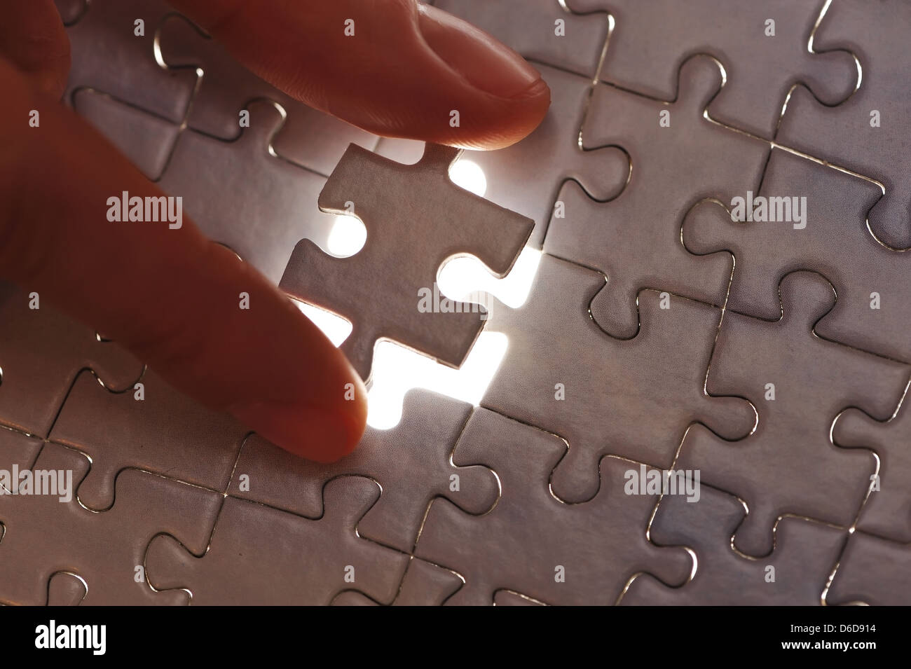 Hand placing missing puzzle piece Stock Photo - Alamy