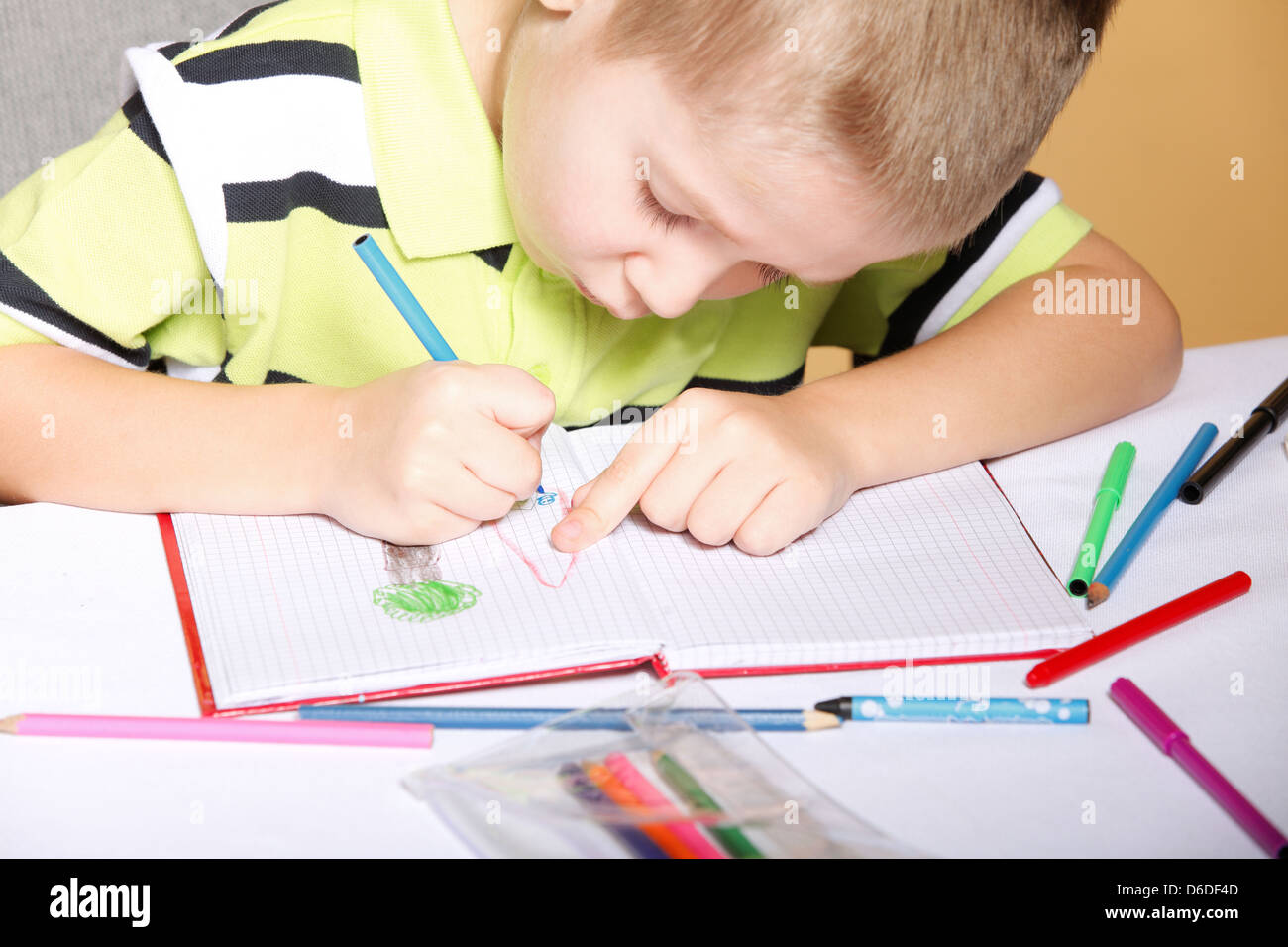 little boy drawing with color pencils on orange background Stock Photo ...