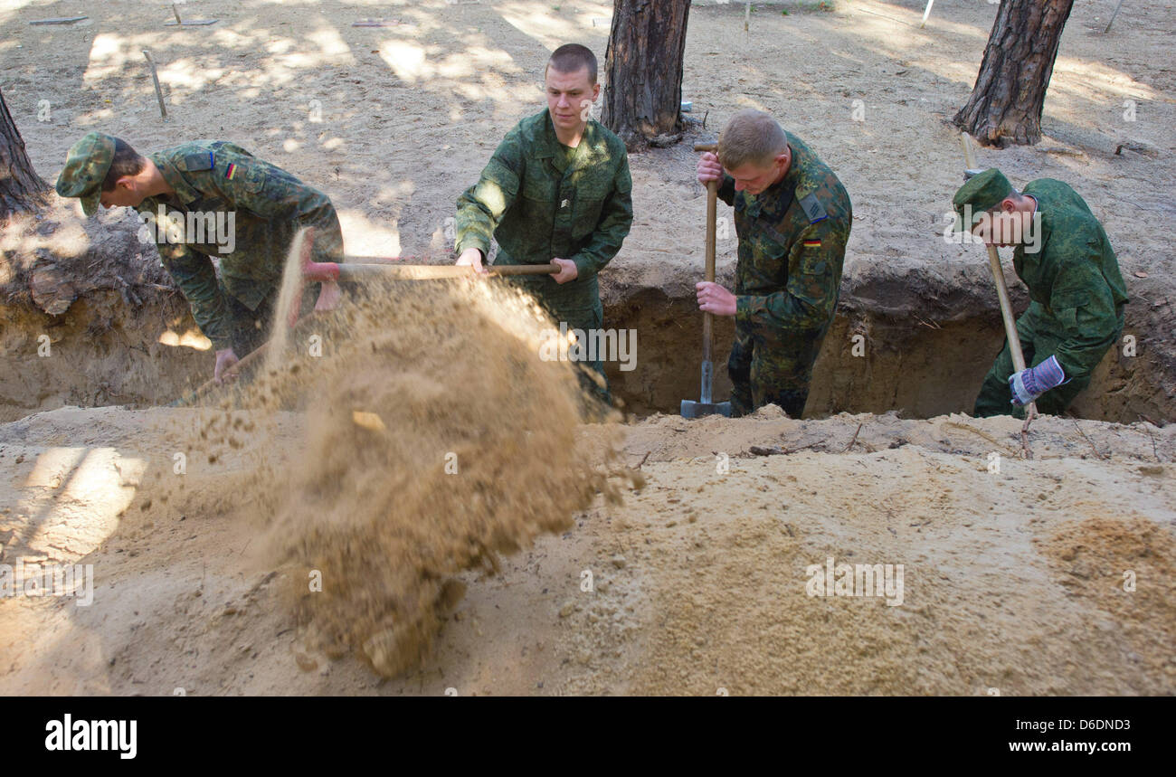 German and Russian soldiers dig a grave for the transfer of remains of ...