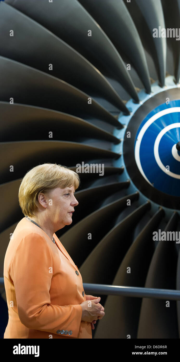 German Chancellor Angela Merkel stands in front of an engine at the ...