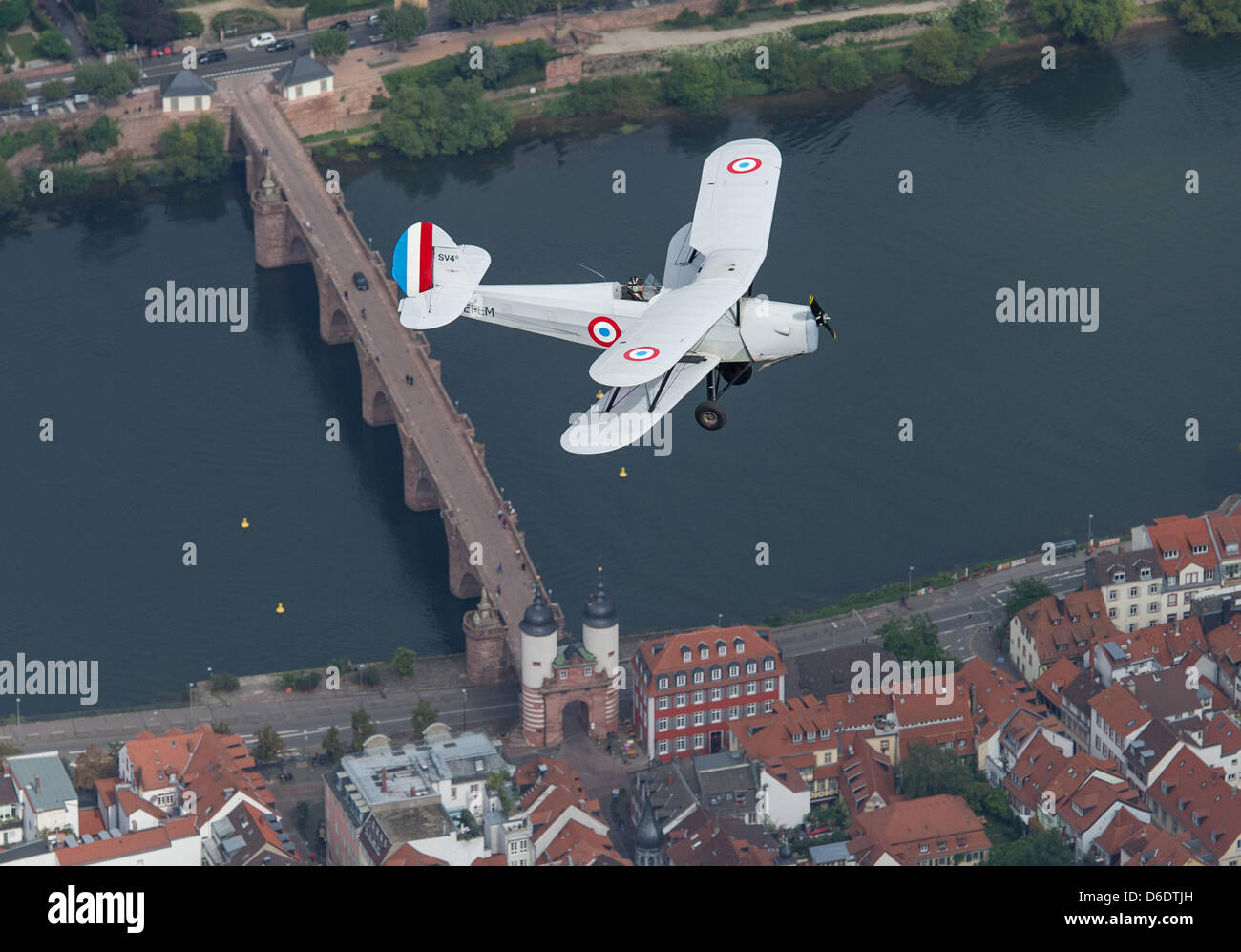 A historic biplane flies over the Neckar and the Old Bridge in ...