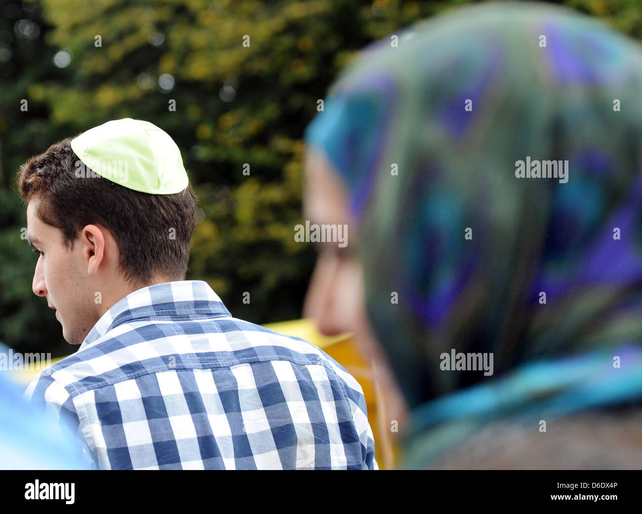 A muslim woman wearing a headscarf and a man with a kippah walk ...