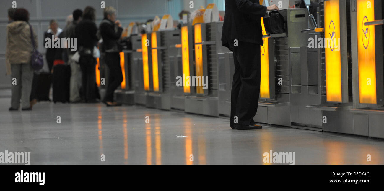 Passengers stand at a check-in counter of Lufthansa at the airport in ...