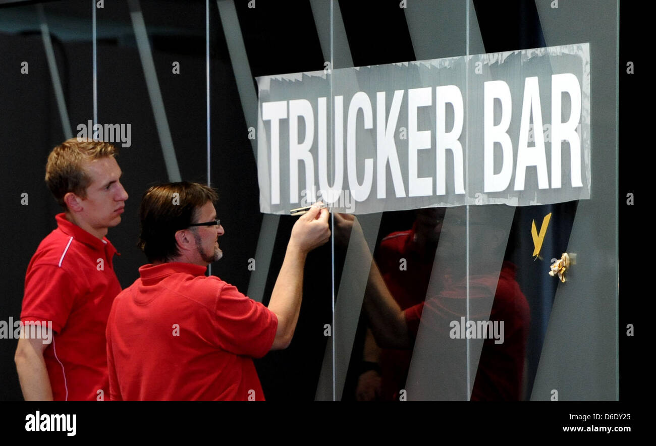 Two employees attach the sign 'Trucker Bar' to a wall during the ...