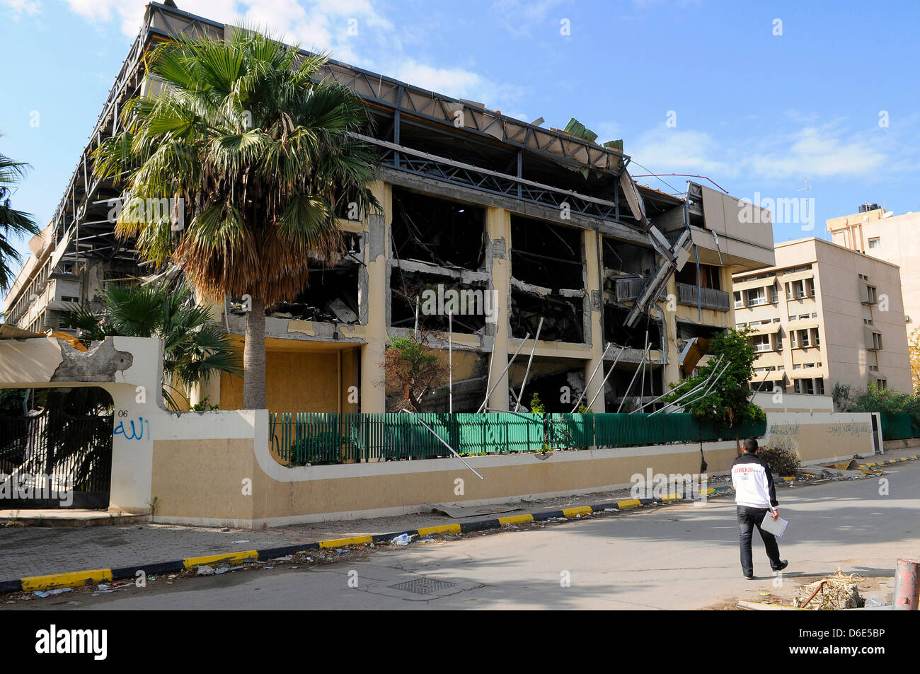 A man walks past a destroyed office building in the Bab al-Azizia ...