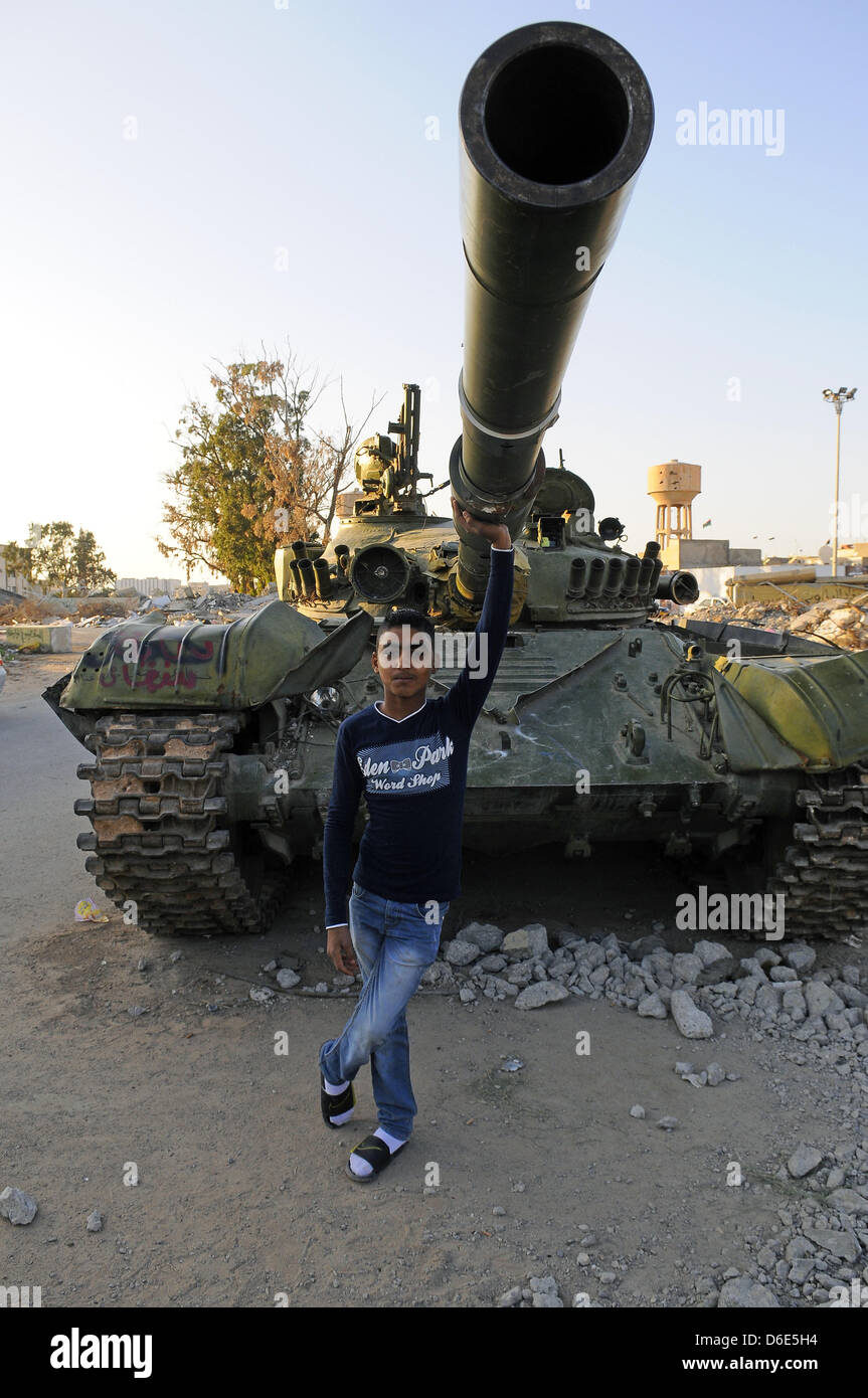 A young man stands in front of a deserted tank in the Bab al-Azizia ...