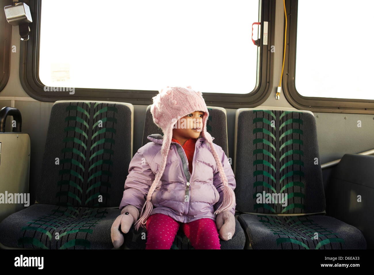 Mixed race girl in hat and gloves riding bus Stock Photo - Alamy