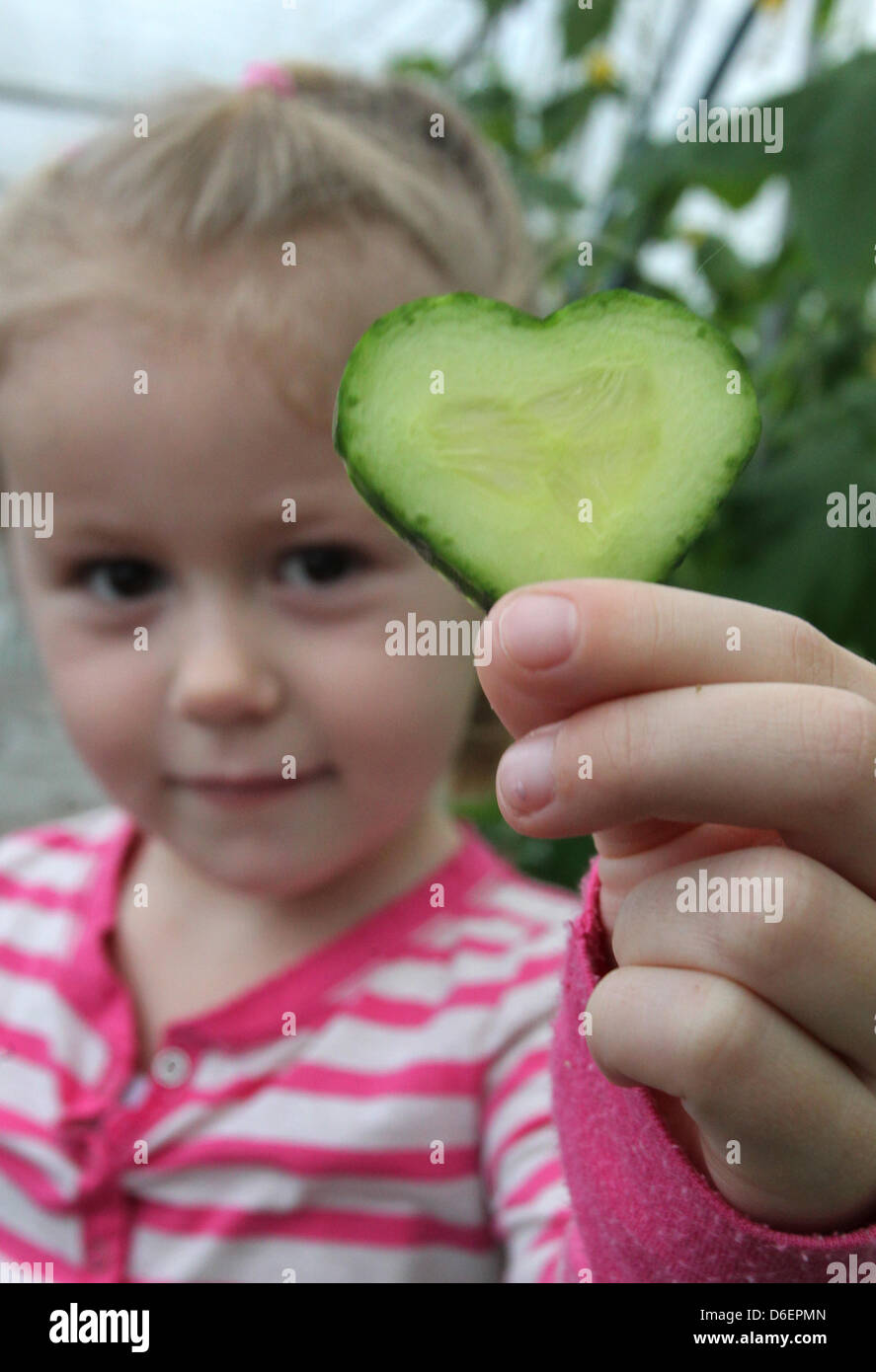 Four-year-old Leni presents a piece of a heart-shaped cucumber at a ...
