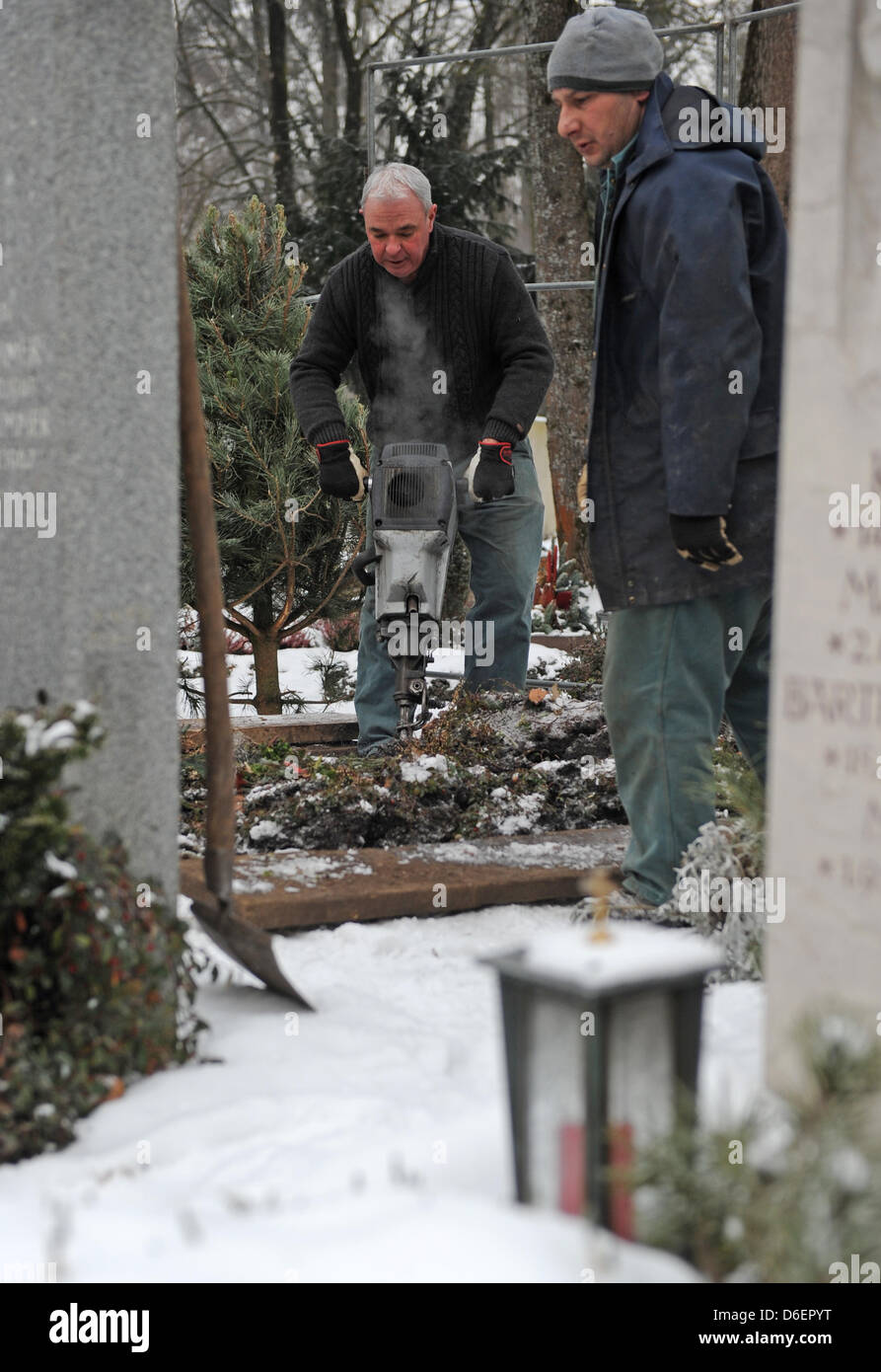 Gravedigger Josef Weiland (L) tries to dig a grave with the help of an ...
